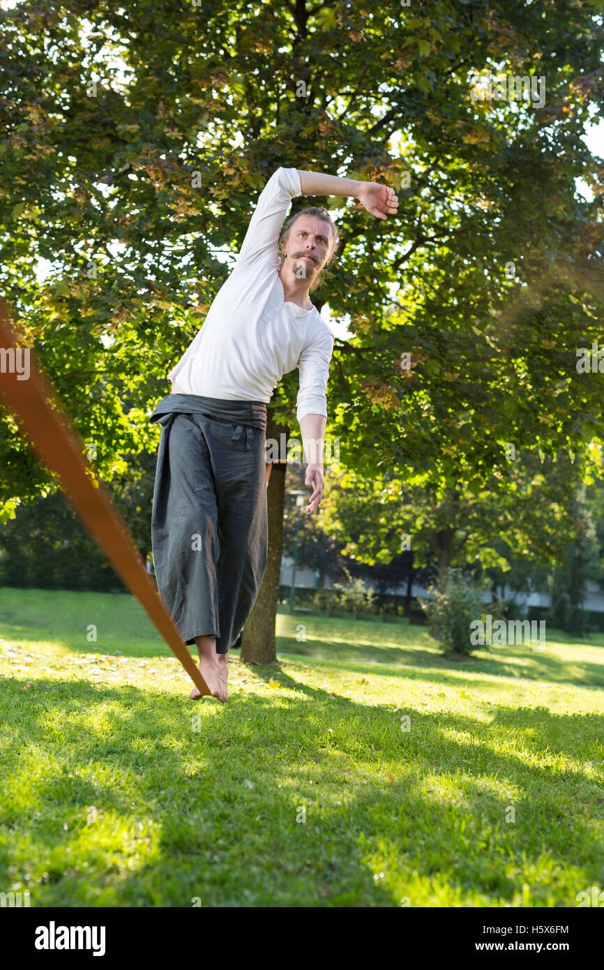 Guy practising slack line in the city park Stock Photo - Alamy