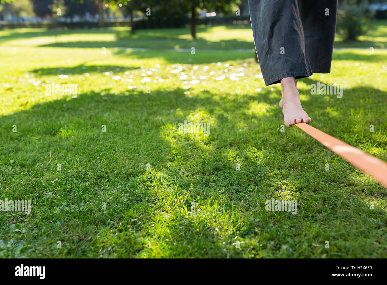 Closeup mans feet from behind balancing on slackline Stock Photo - Alamy