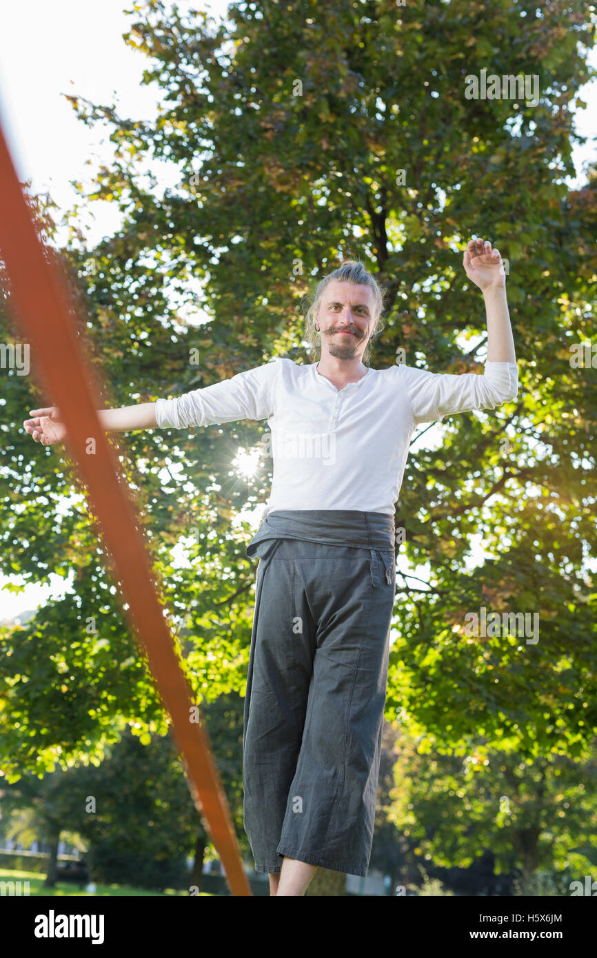 Guy practising slack line in the city park Stock Photo - Alamy