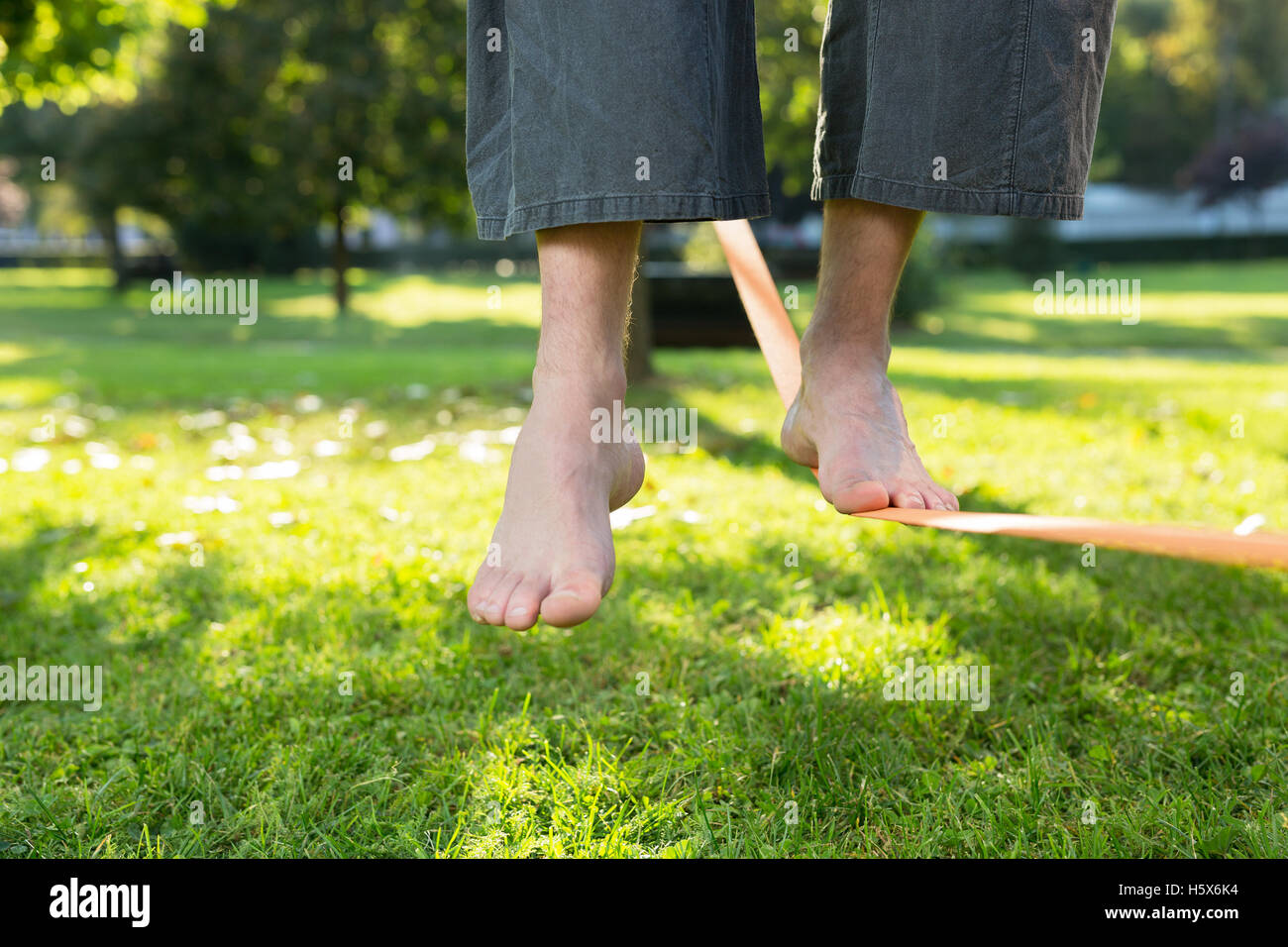 Closeup of mans feet balancing a tightrope or slackline in park ...