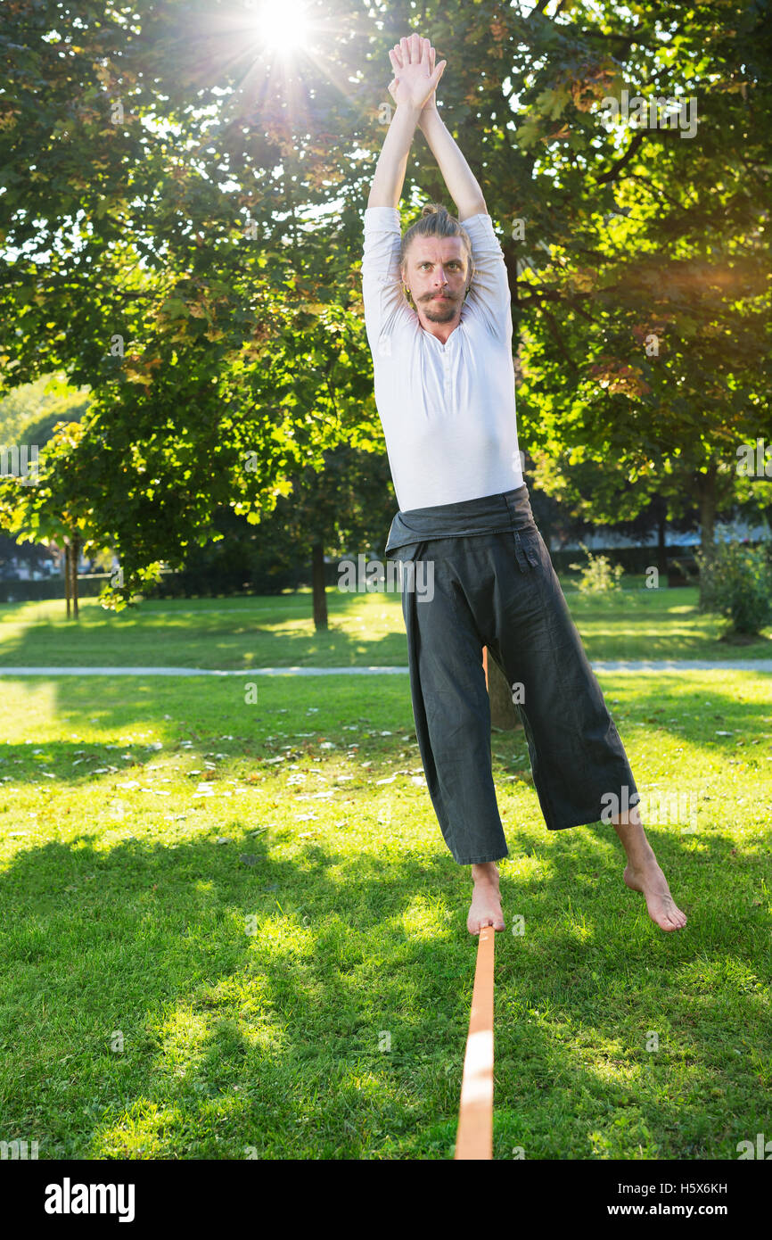 Guy practising slack line in the city park Stock Photo - Alamy