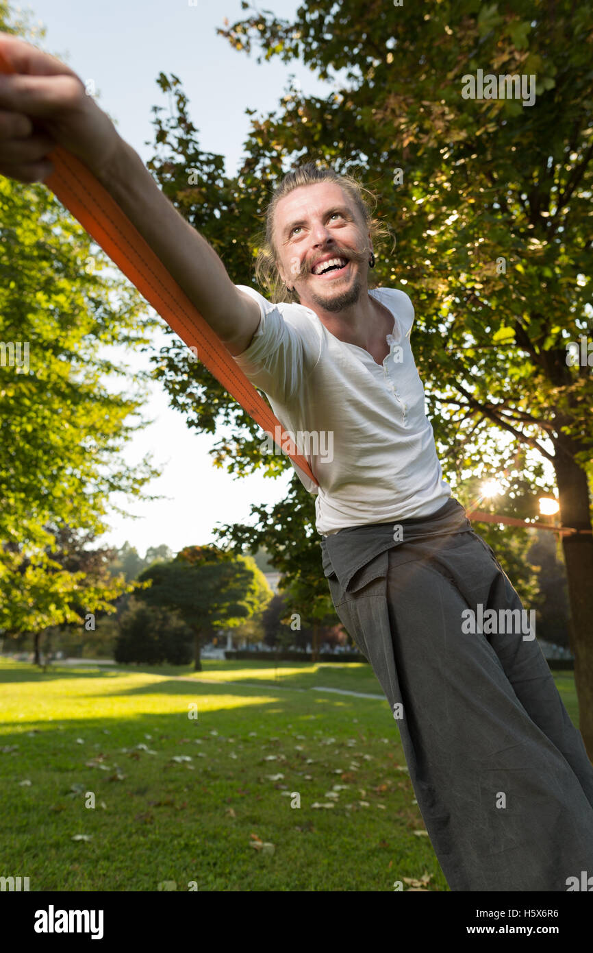 Guy practising slack line in the city park Stock Photo - Alamy