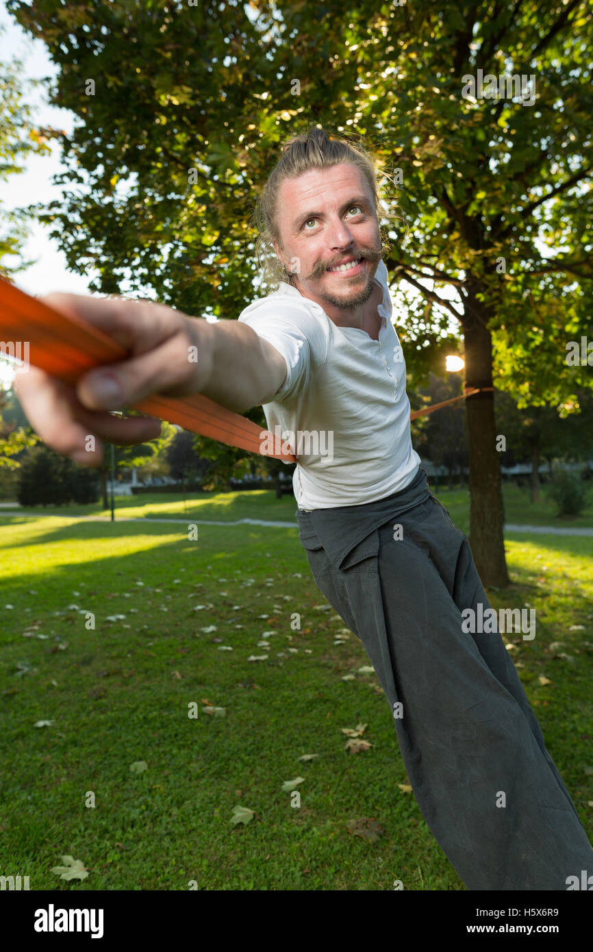 Guy practising slack line in the city park Stock Photo - Alamy