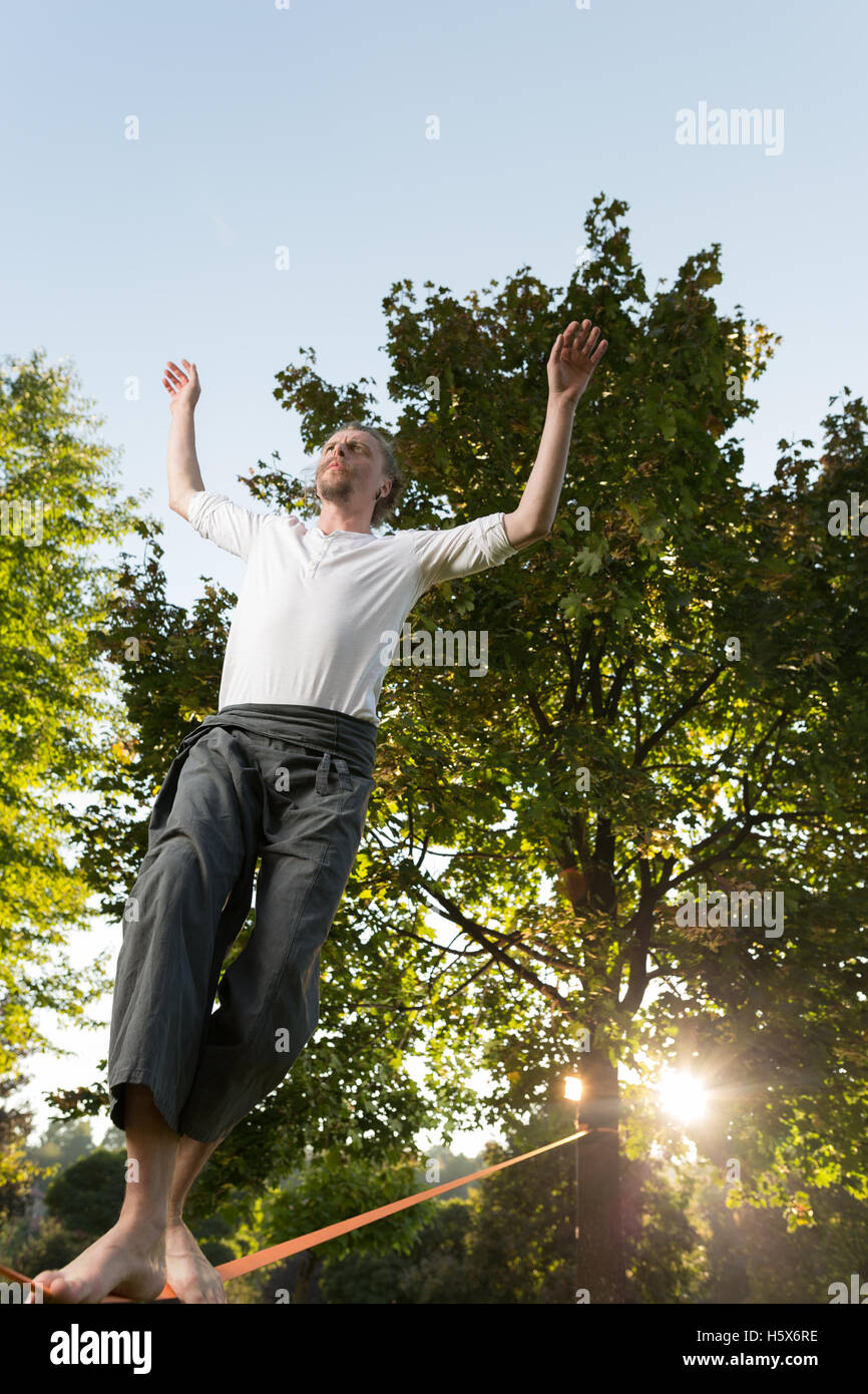 Guy practising slack line in the city park Stock Photo - Alamy