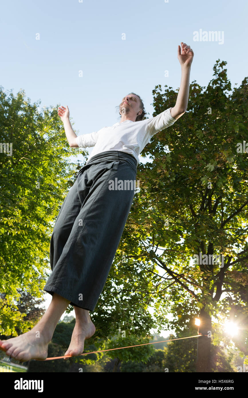 Guy practising slack line in the city park Stock Photo - Alamy