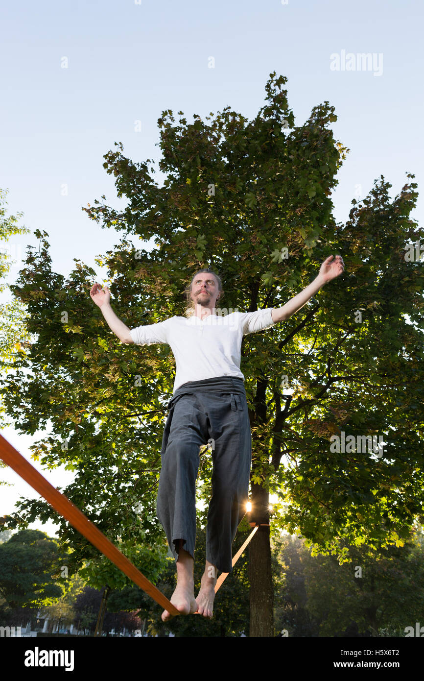 Guy practising slack line in the city park Stock Photo - Alamy