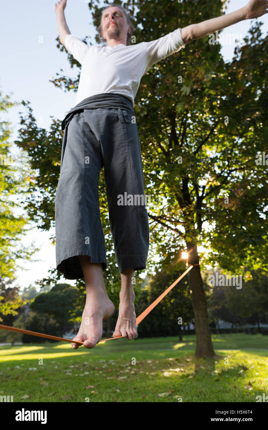 Guy practising slack line in the city park Stock Photo - Alamy
