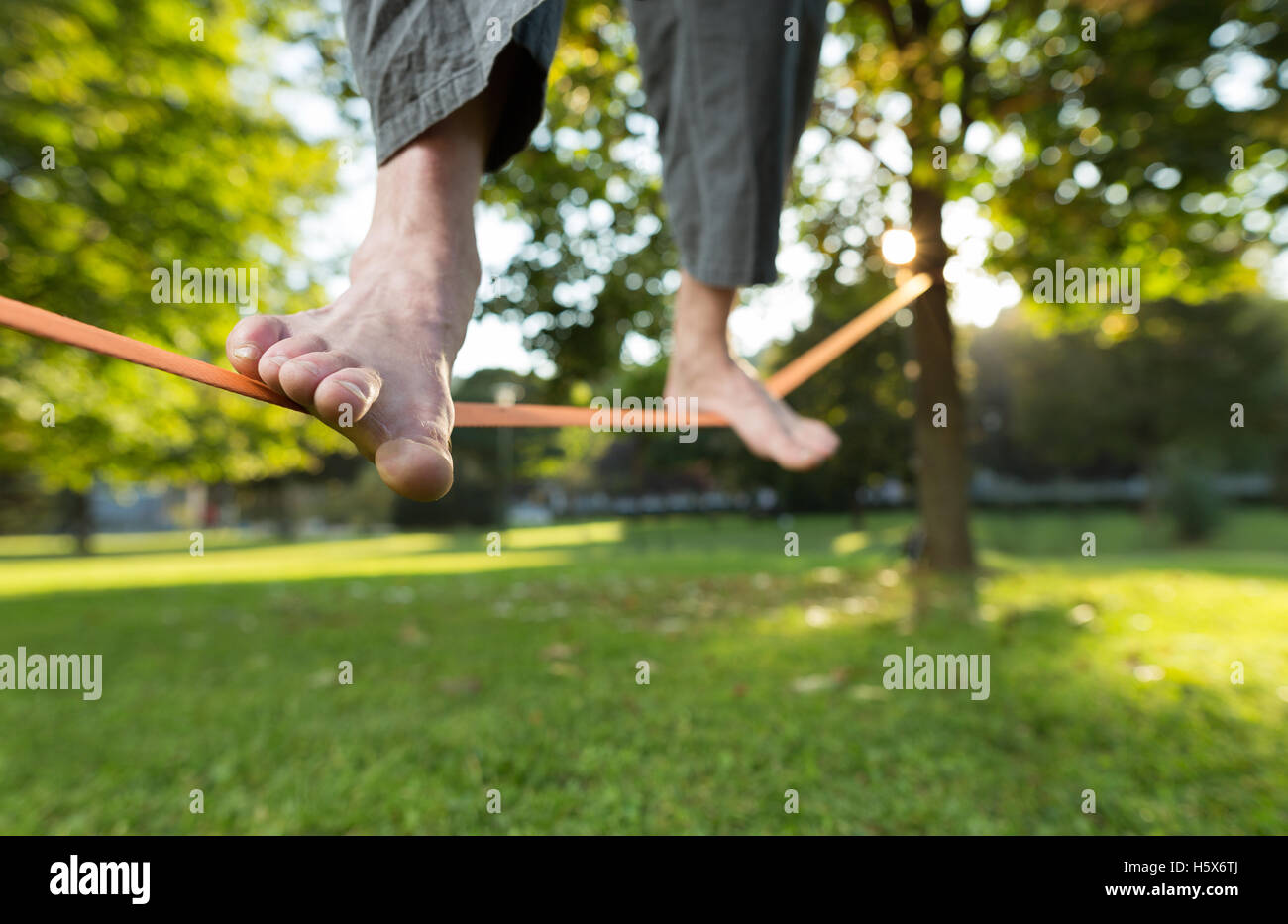 Closeup mans feet from behind balancing on slackline Stock Photo - Alamy
