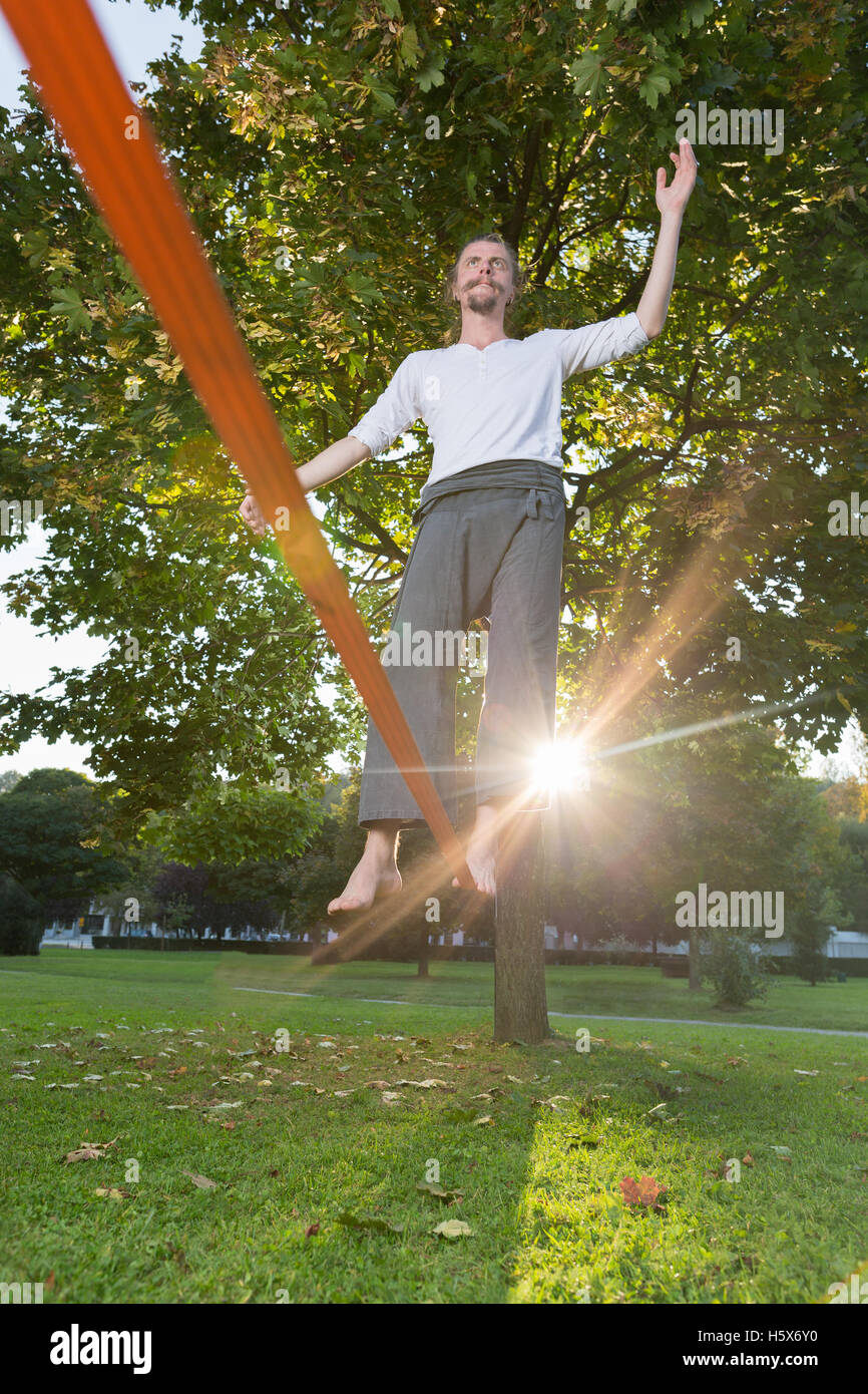 Guy practising slack line in the city park Stock Photo - Alamy