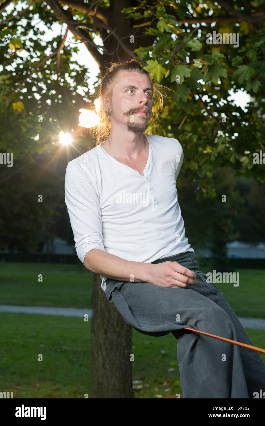 Man sitting on tightrope or slackline concentrating to keep balance ...