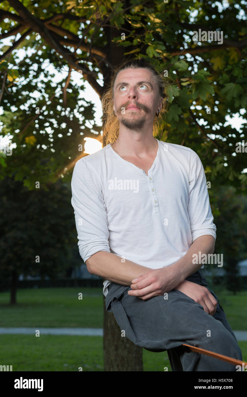 Portrait of man sitting on slackline and resting Stock Photo - Alamy