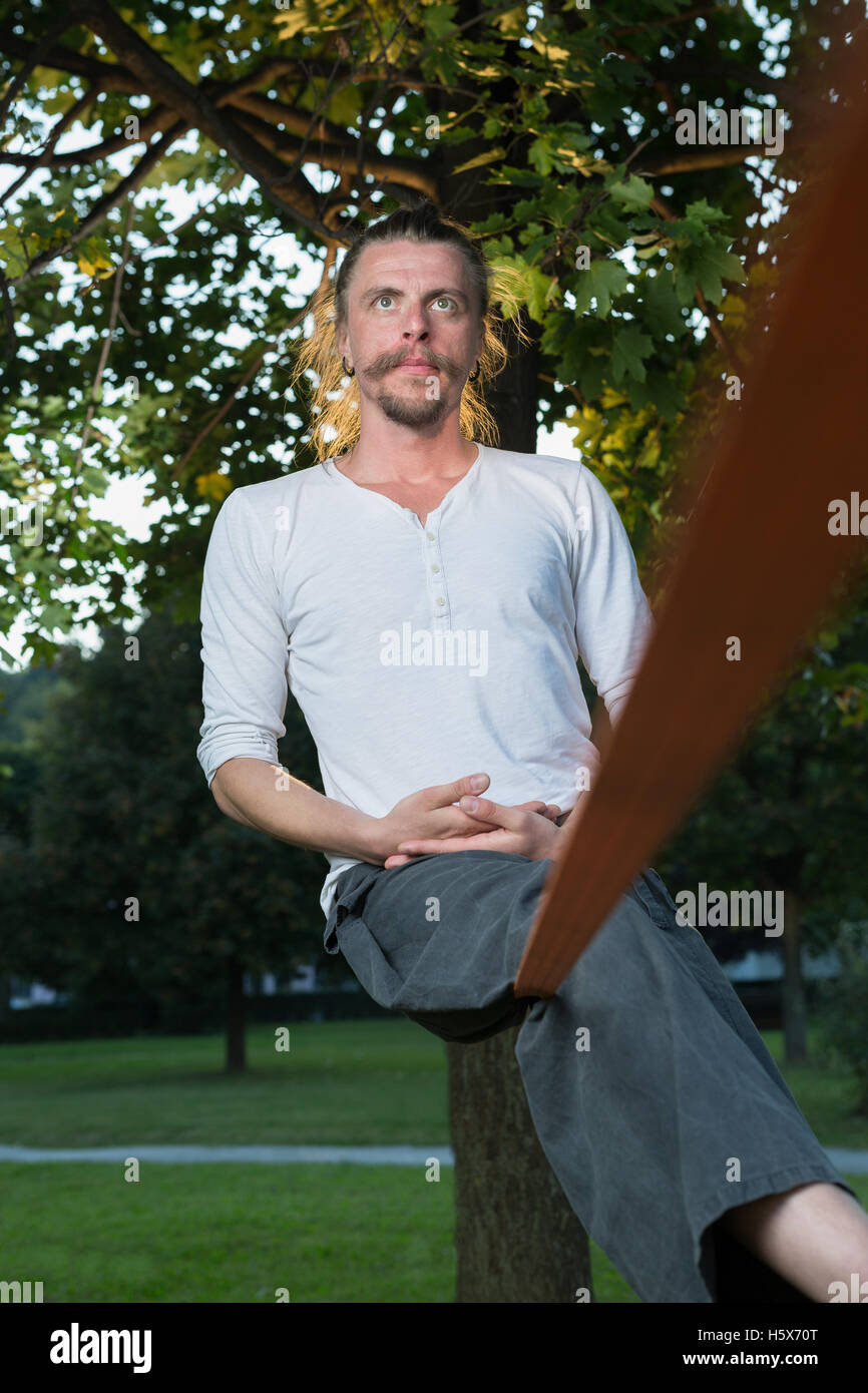 Portrait of man sitting on slackline and resting Stock Photo - Alamy