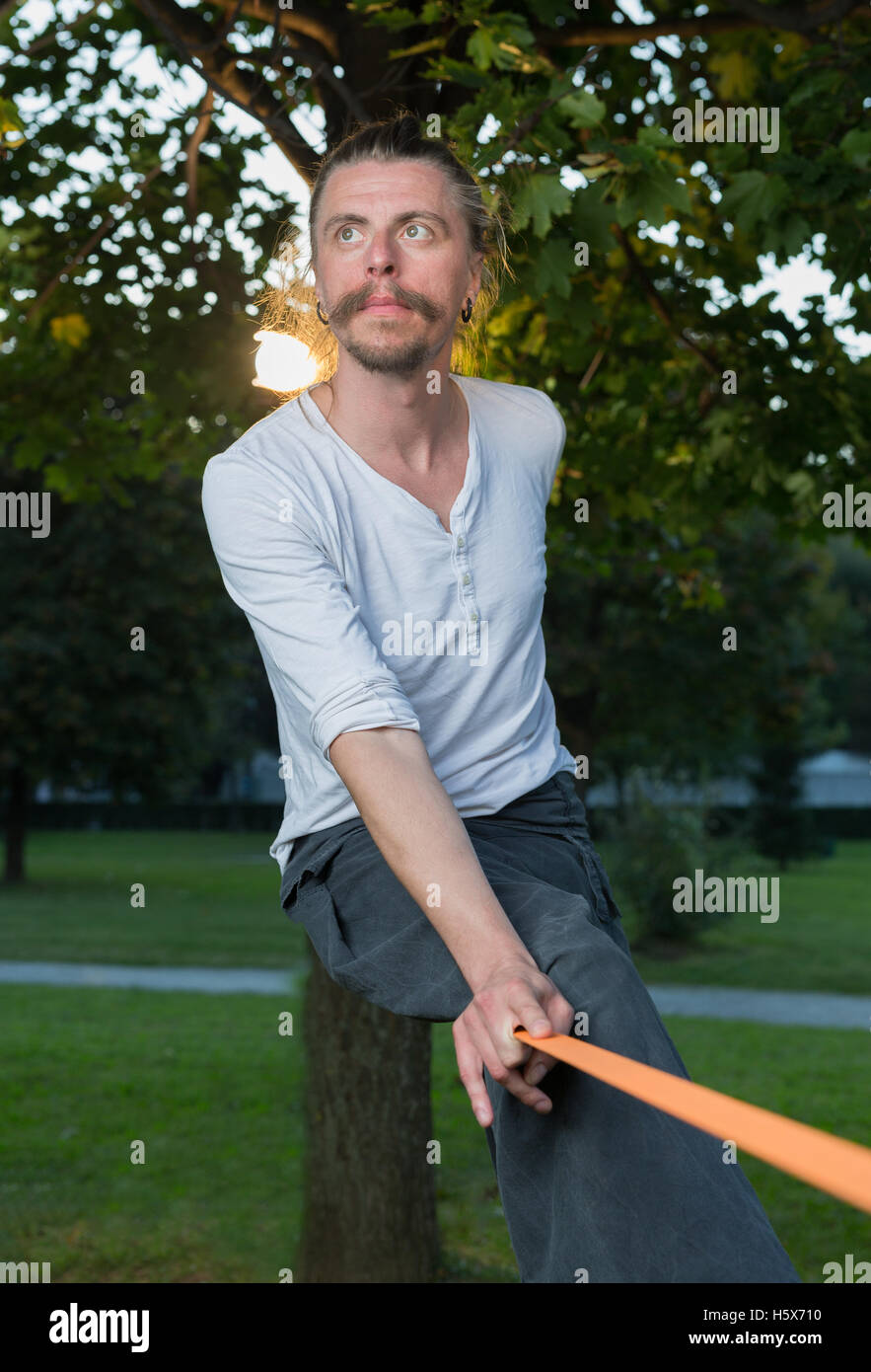 Portrait of man sitting on slackline and resting Stock Photo - Alamy