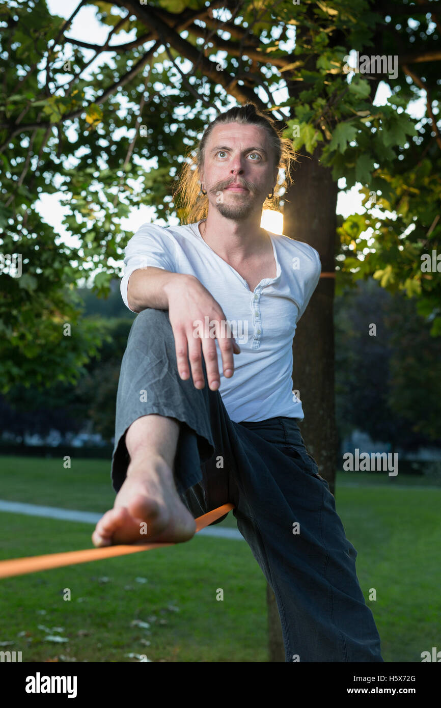 Portrait of man sitting on slackline and resting Stock Photo - Alamy