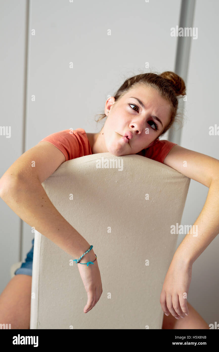 Teen putting faces funny, sitting in a Chair mouth down. Vertical image ...
