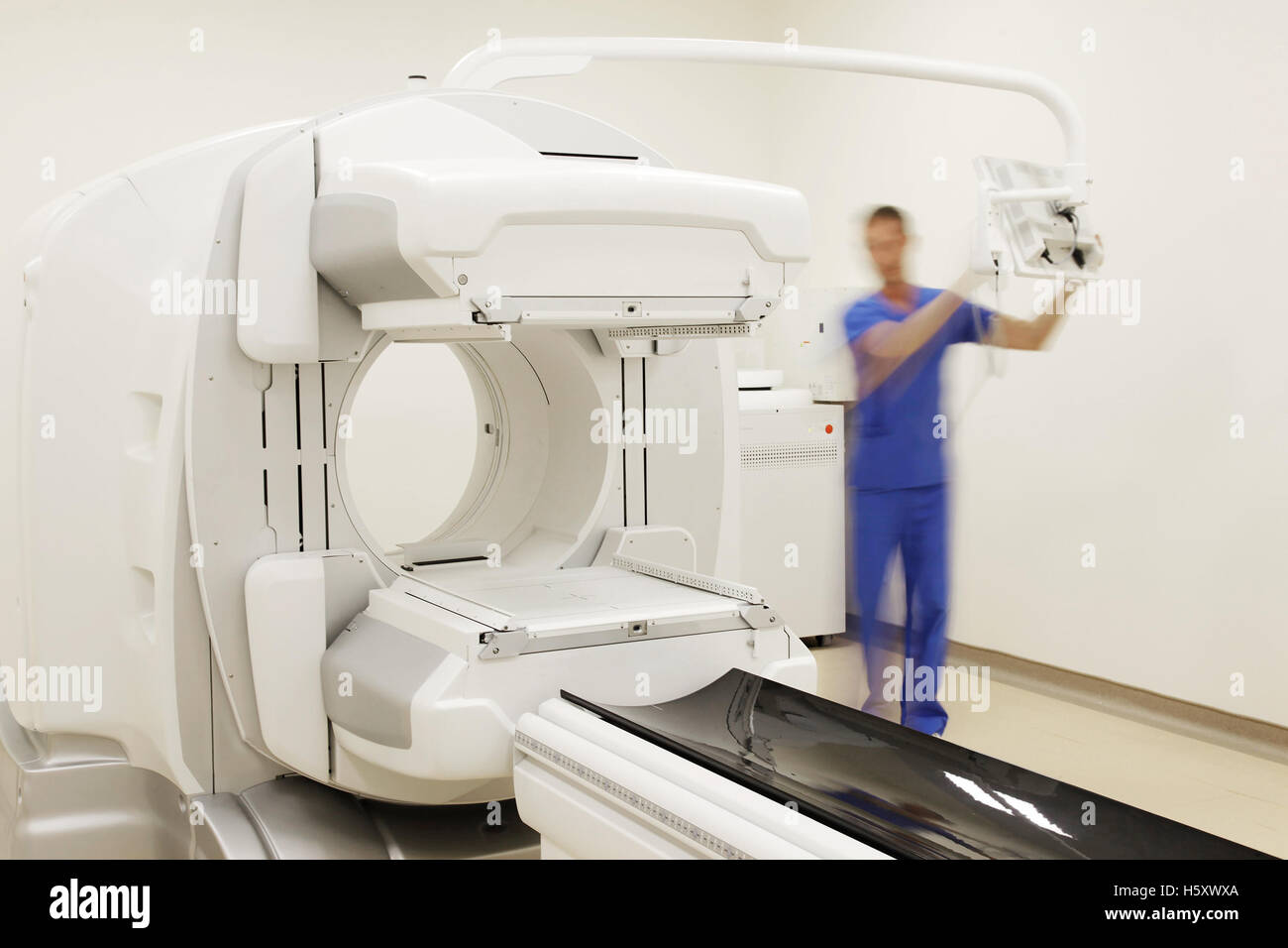A blurred figure of a doctor preparing an x-ray scanner in modern ...