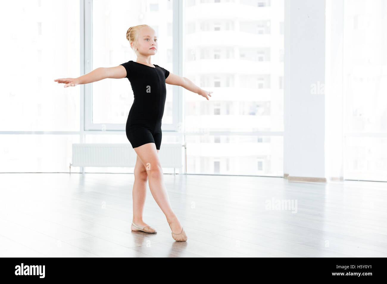 Little cute girl is busy performing exercises in the studio Stock Photo ...