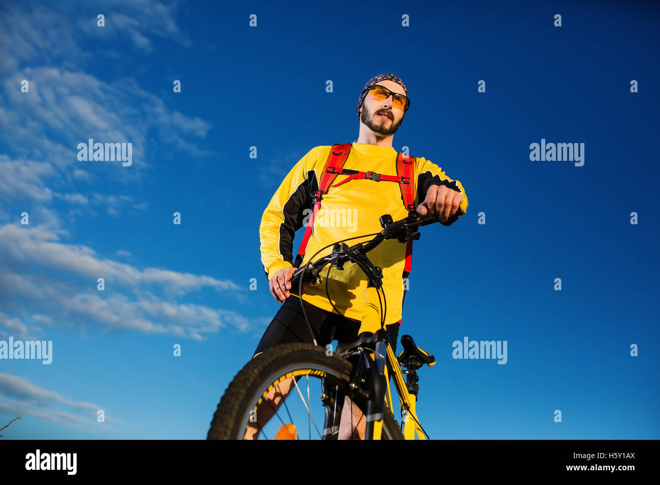 Cyclist man standing on top of a mountain with bicycle and enjoying ...