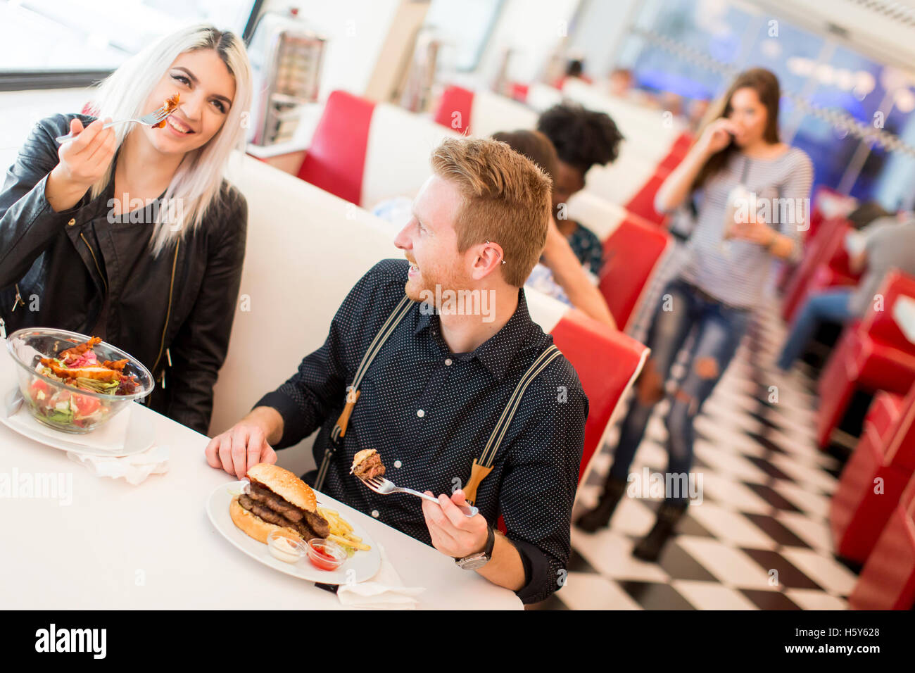 Friends eating fast food at the table in the diner Stock Photo - Alamy