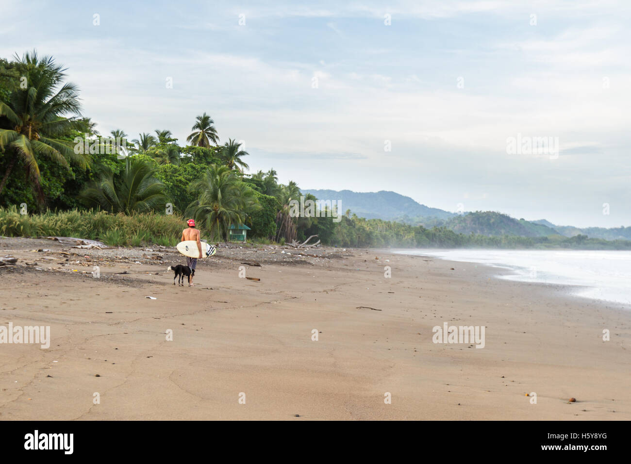 Tambor, Costa Rica - June 20: Young surfer walking the beach with his ...