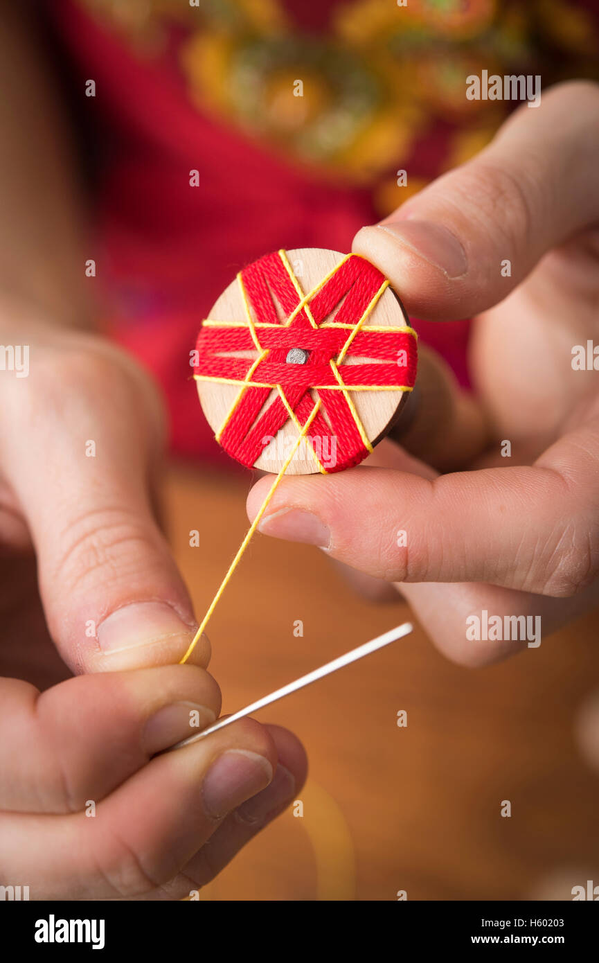 Button maker stitching and wrapping red and yellow yarn into star ...