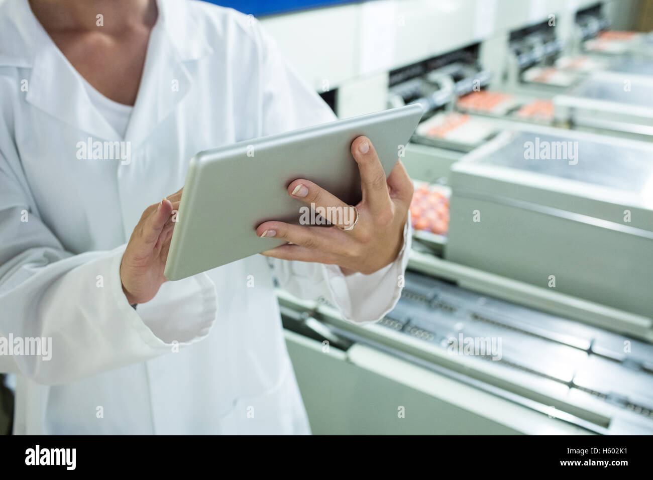 Mid section of female staff using digital tablet next to production ...