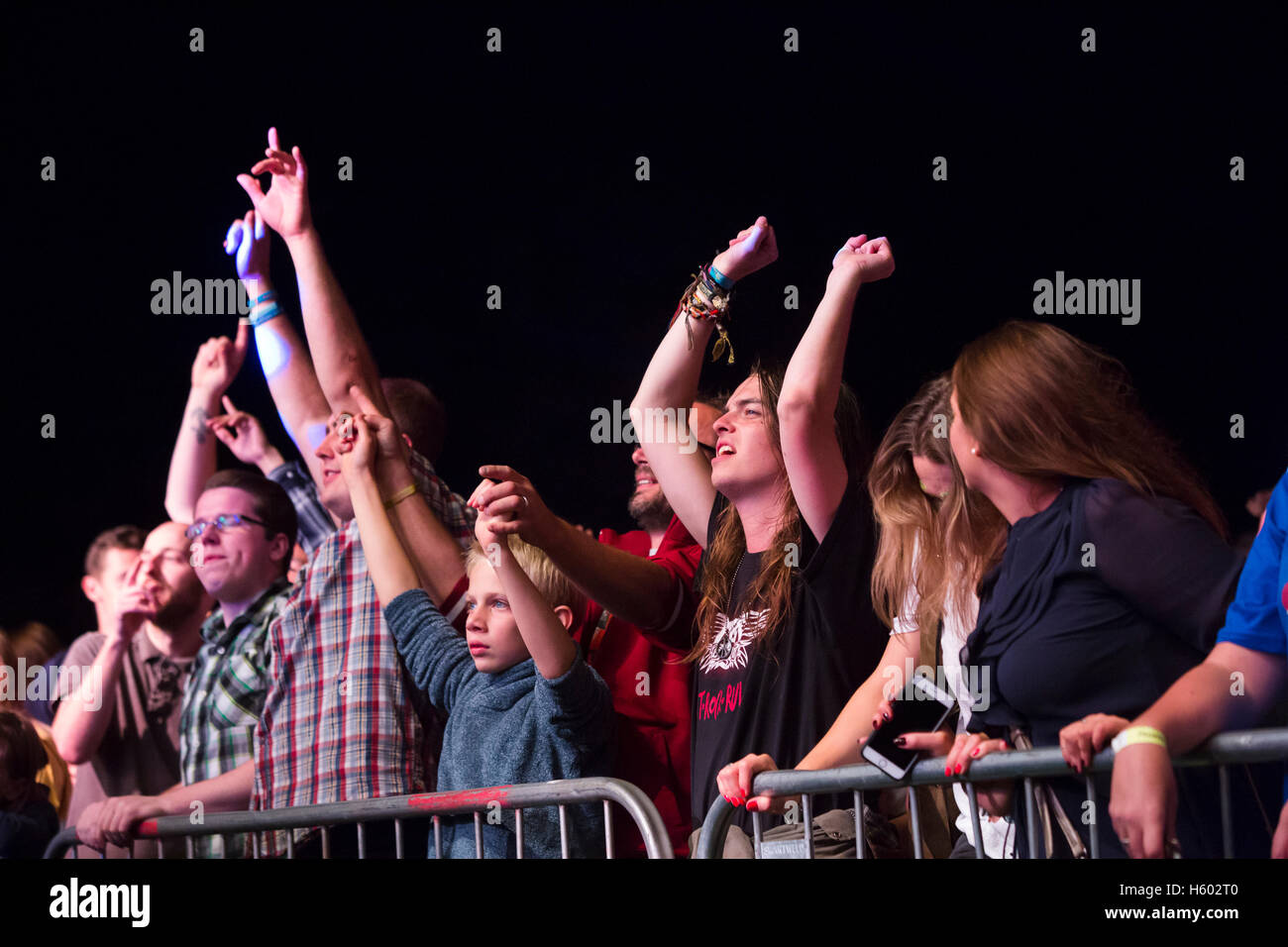 Crowds watch an Oasis tribute band play an atmospheric night time ...