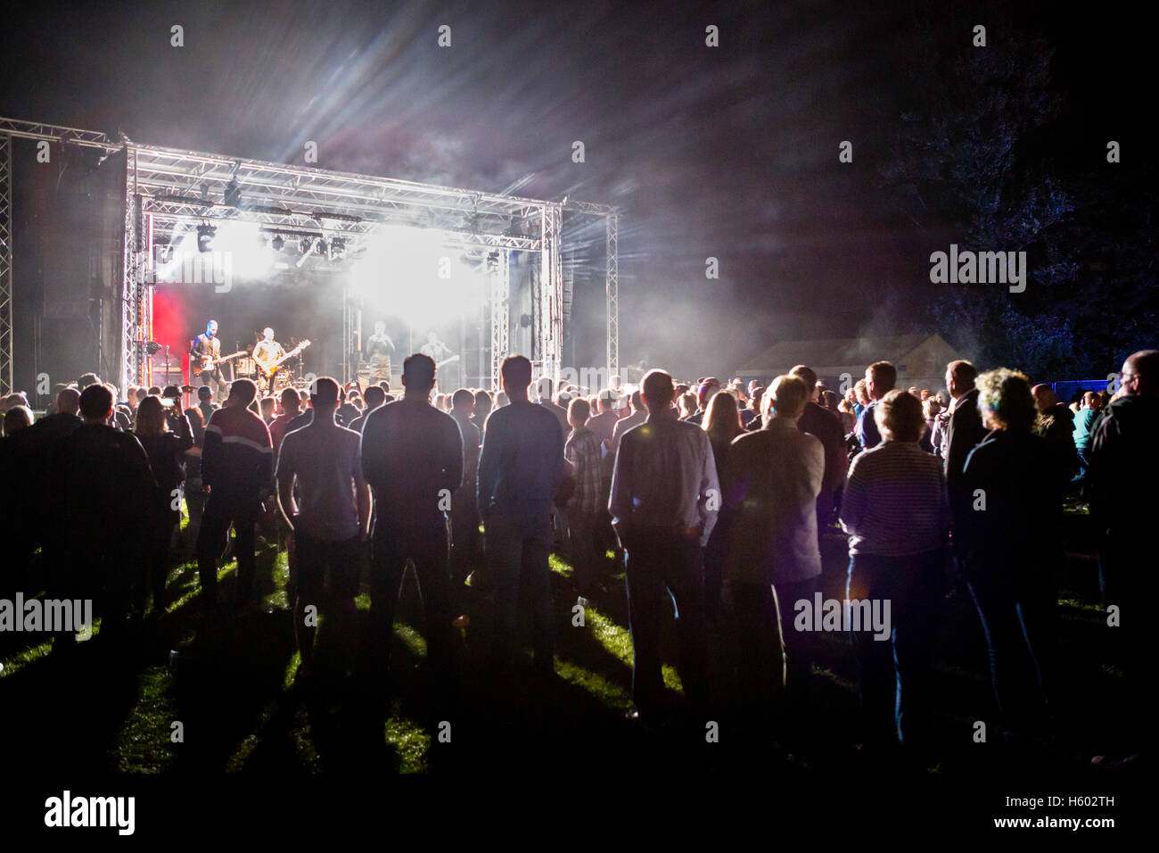 Crowds watch an Oasis tribute band play an atmospheric night time ...