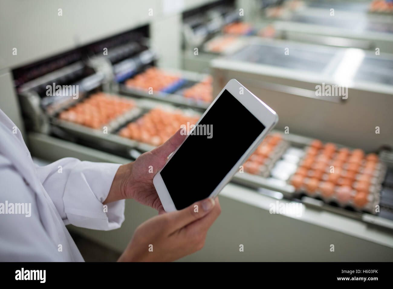 Mid section of female staff using digital tablet next to production ...