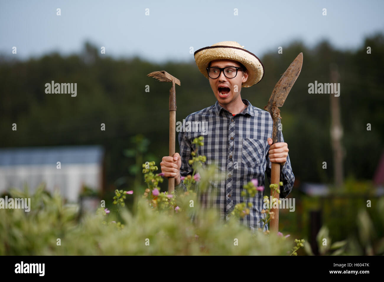 Funny expressive portrait of farmer man with shovel and rake screaming ...