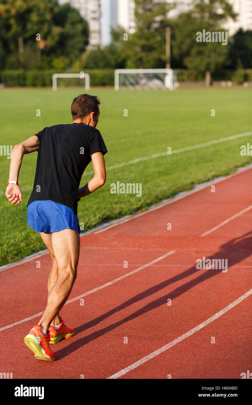 Man jogging on summer day on running track at football field Stock ...