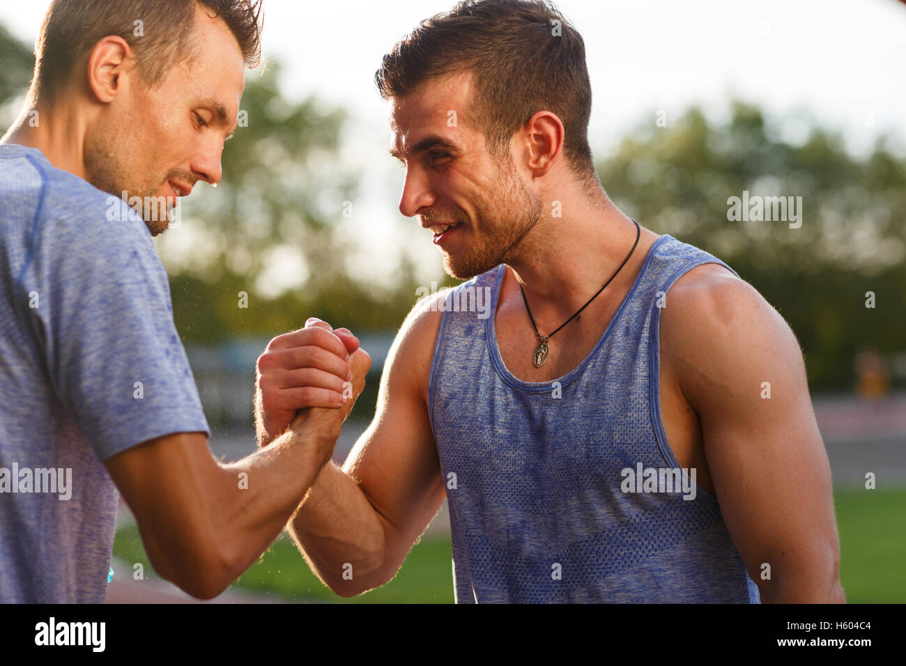 Two strong handsome man greet each other and shake hands during workout ...