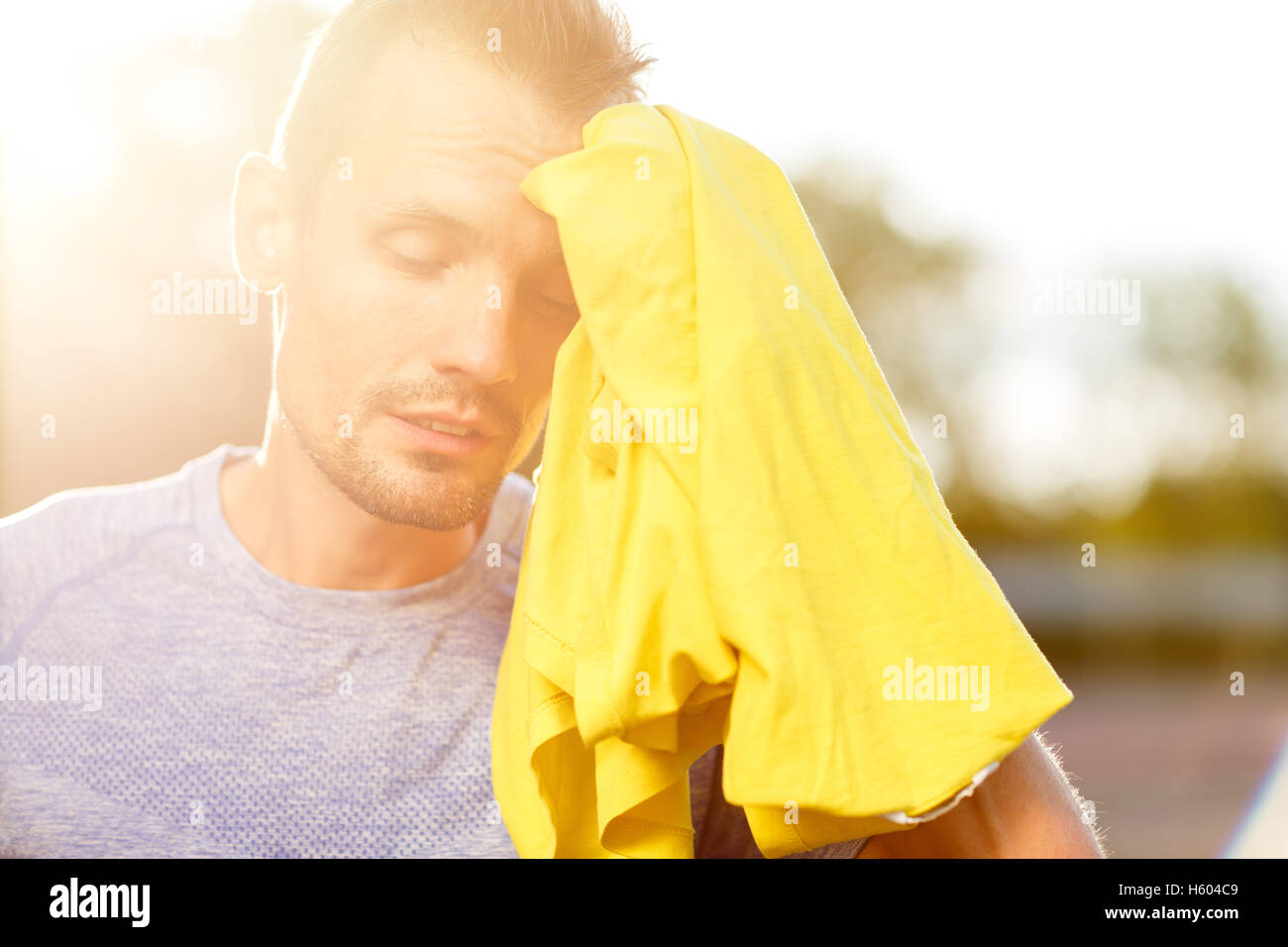 Tired athletic man wiped towel after workout. Image with lens flare ...