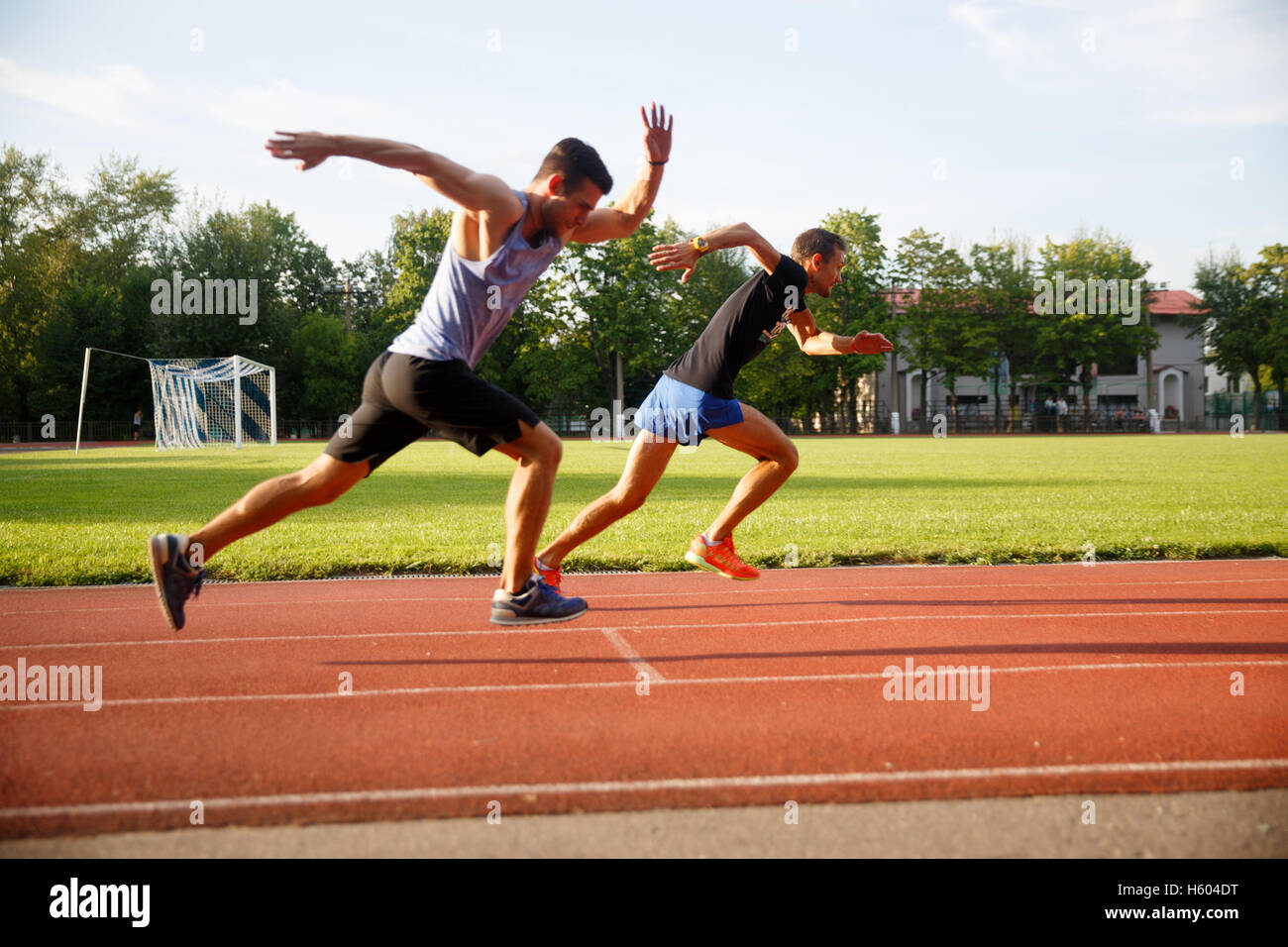 Handsome strong sportsmen quickly running on outdoors track, portrait ...