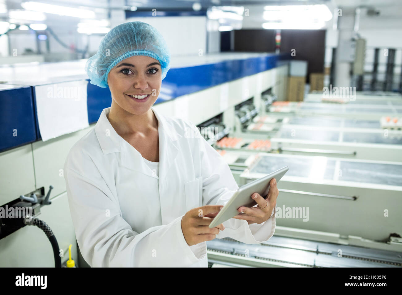 Female staff using digital tablet next to production line Stock Photo ...