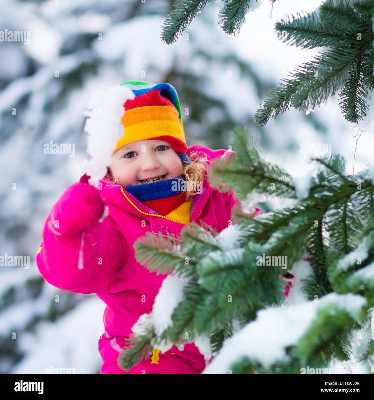 Child playing in snowy forest. Toddler kid holding an icicle outdoors ...