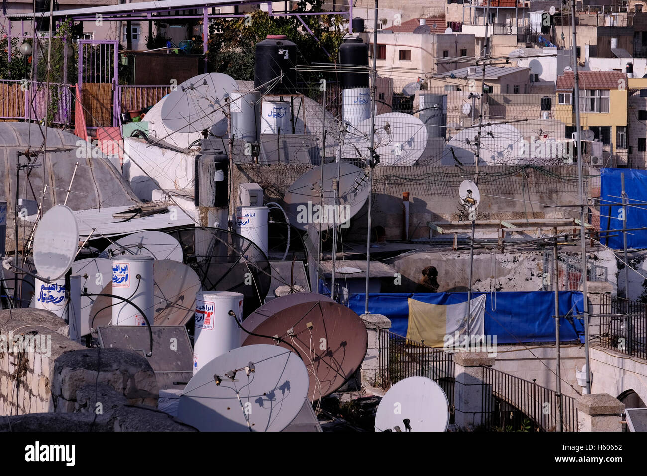 White tanks of water-heaters and satellite dishes on rooftop of houses ...