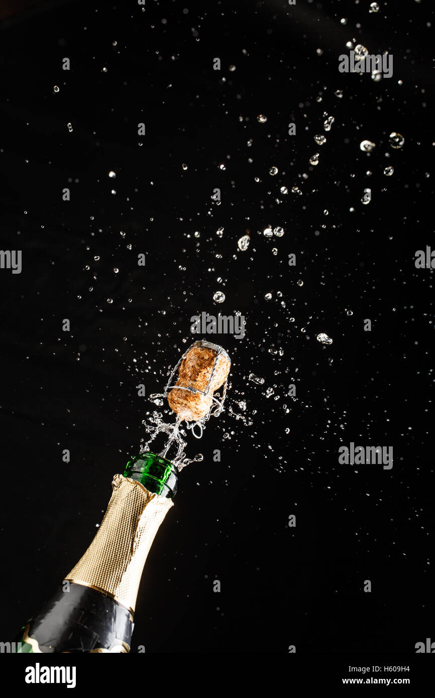 Closeup of champagne explosion. Vertical image on black background ...