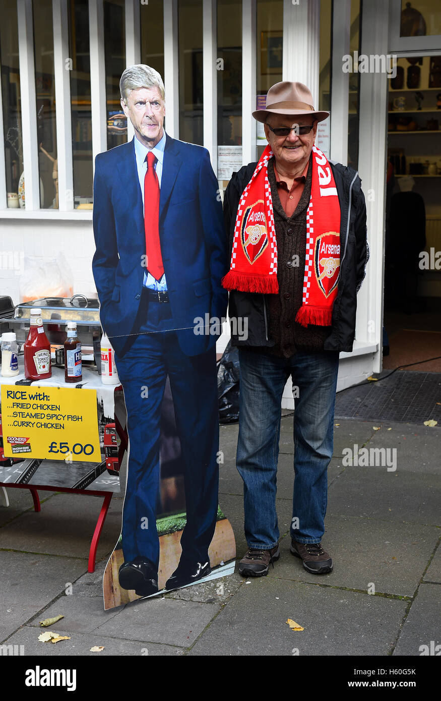 A fan poses with a cardboard cutout of Arsenal manager Arsene Wenger ...