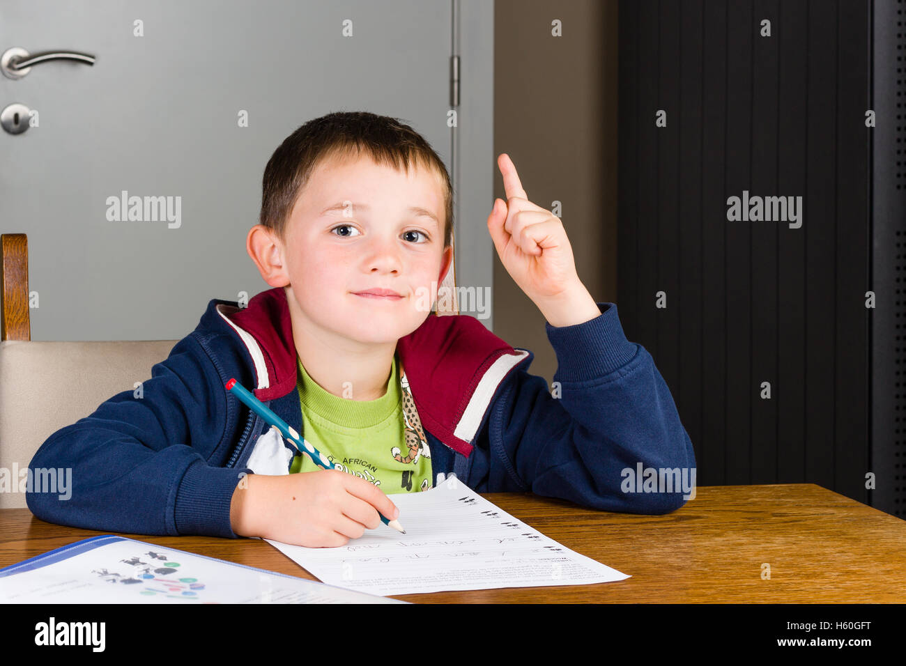 Boy doing homework in a living room raising his finger Stock Photo - Alamy