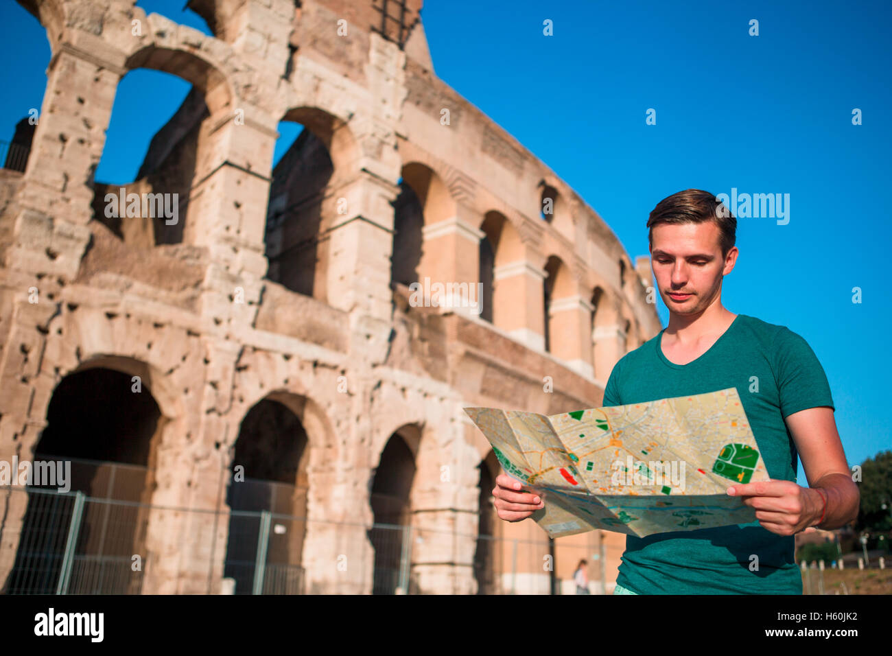 Boy with map in front of Colosseum. Young man searching the attraction ...