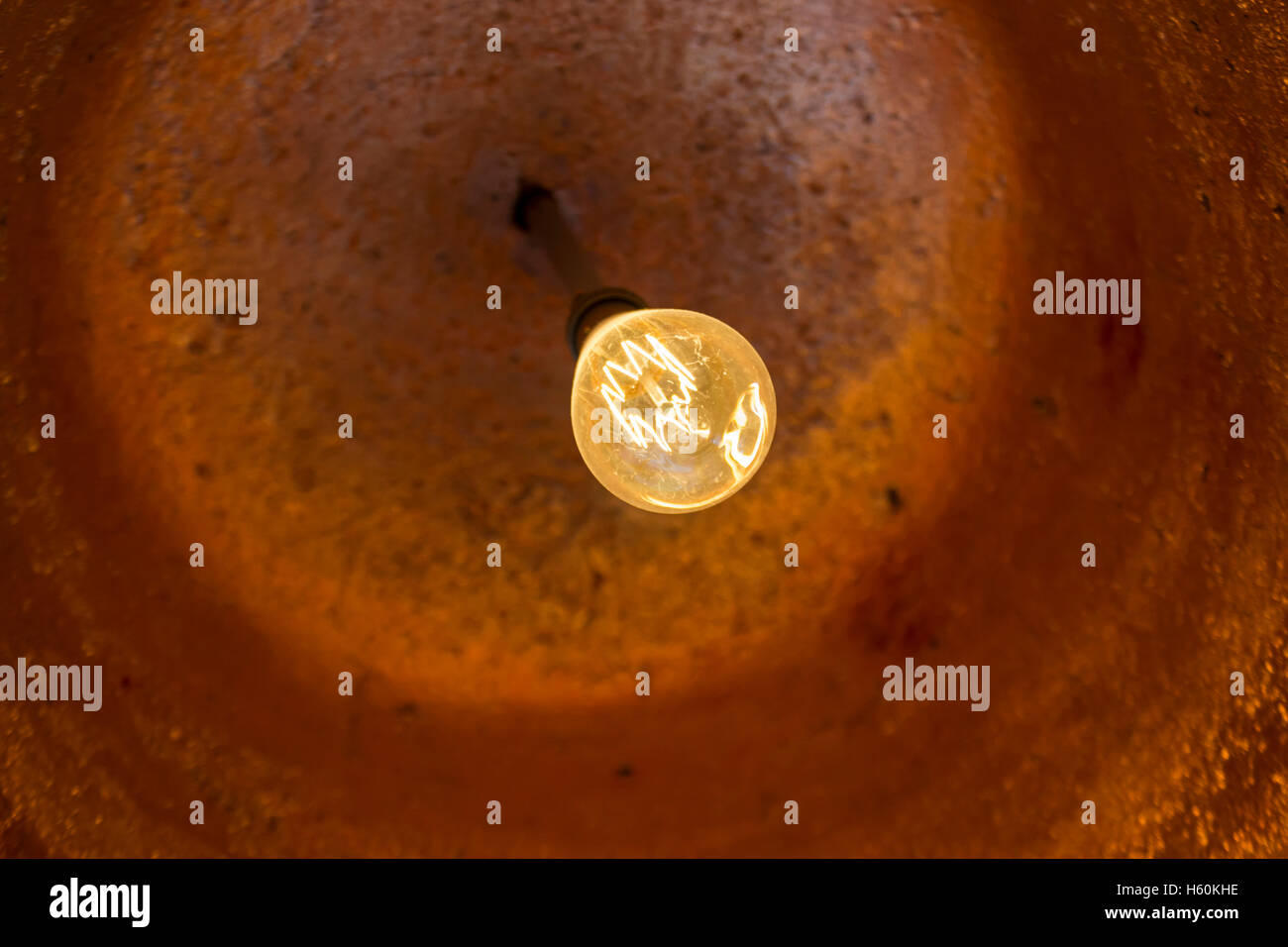 Close up of bulb filament burning inside an orange lampshade Stock ...