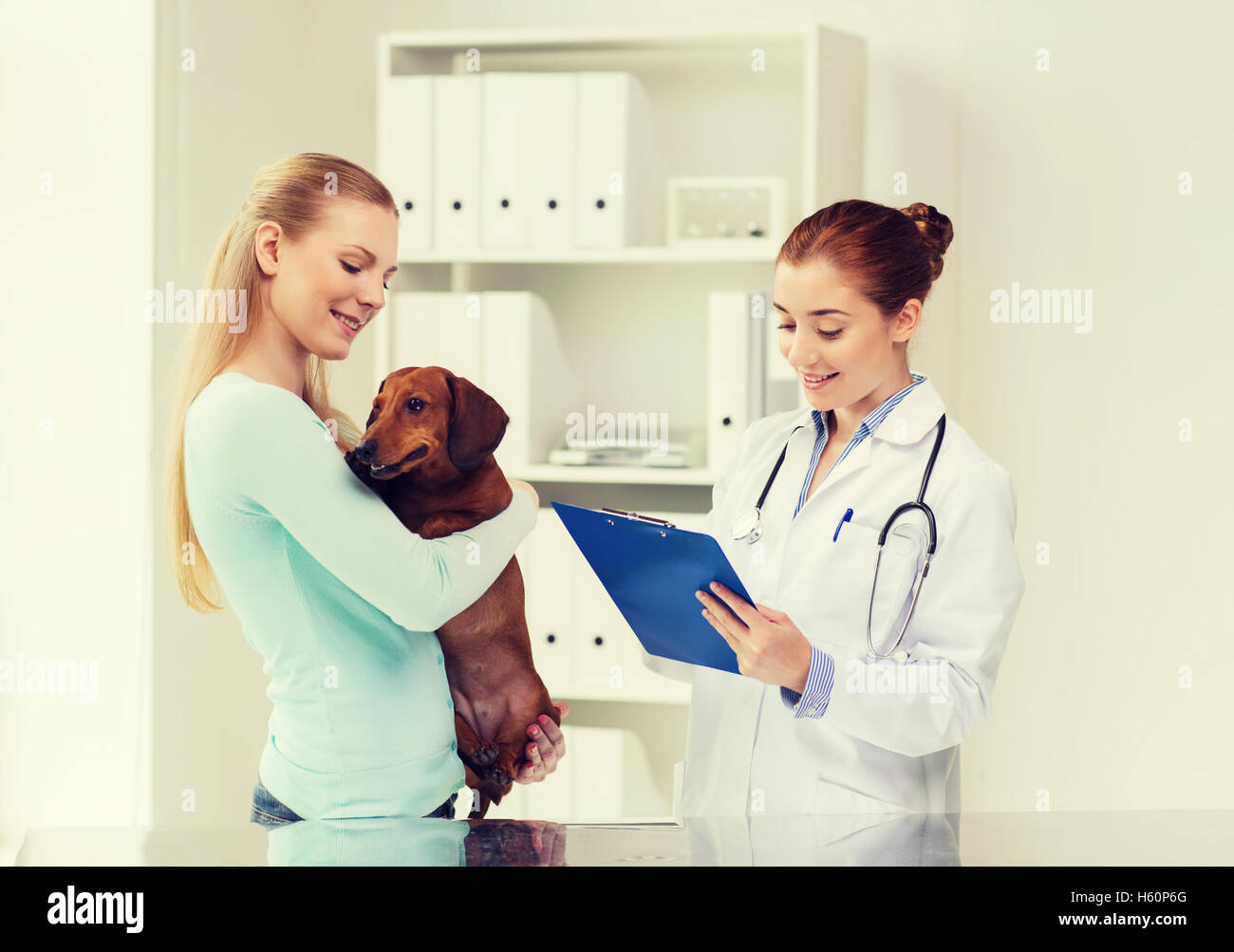 happy woman with dog and doctor at vet clinic Stock Photo - Alamy
