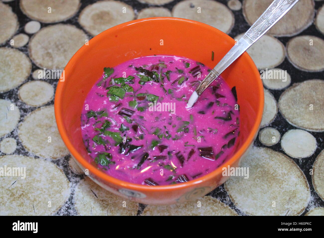 bright pink color soup from young beet in orange bowl with spoon ...