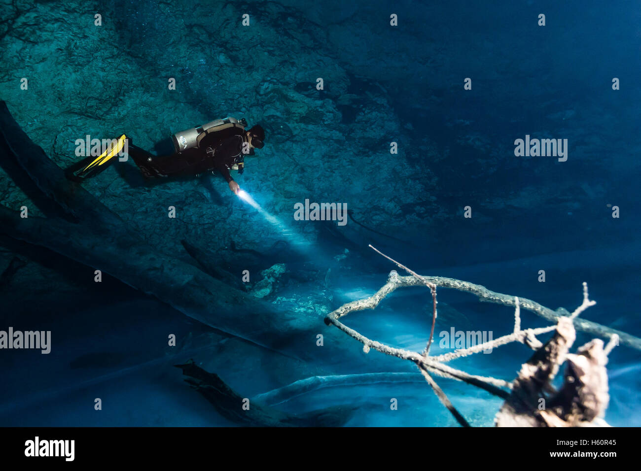 Diver in a cenote cave in Tulum, Mexico, surrounded by turquoise water ...