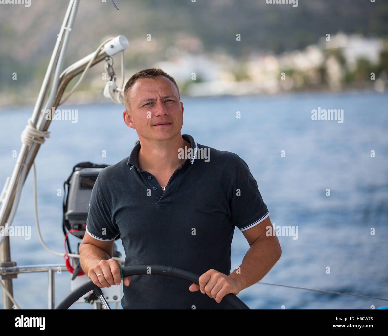 Young man at the helm of a sailing yacht Stock Photo - Alamy
