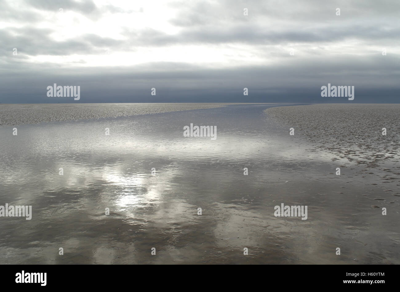 Grey clouds with white sun openings reflecting sea water channel ...
