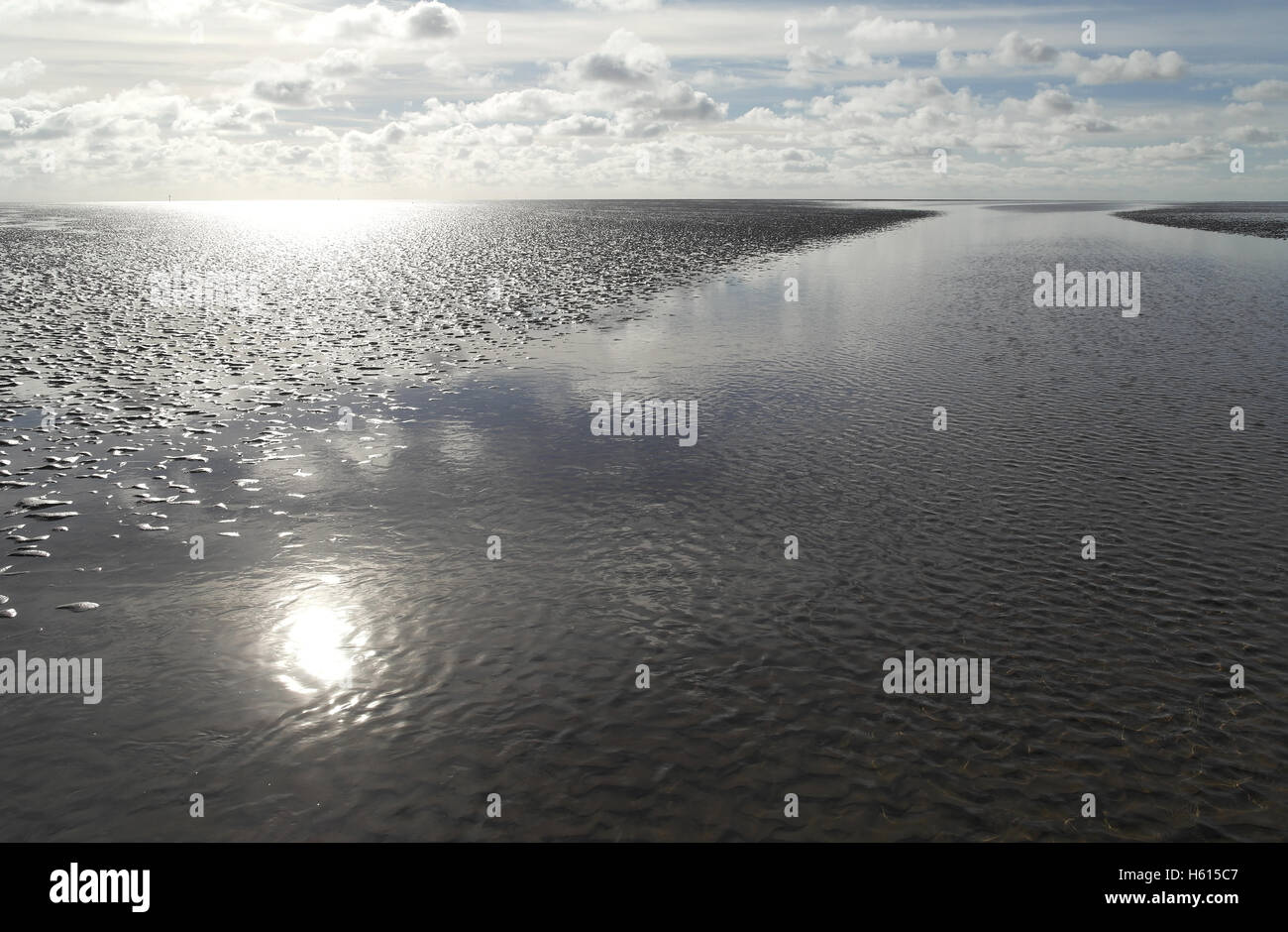 Sea water channel, with white sun reflection, crossing sand beach ...