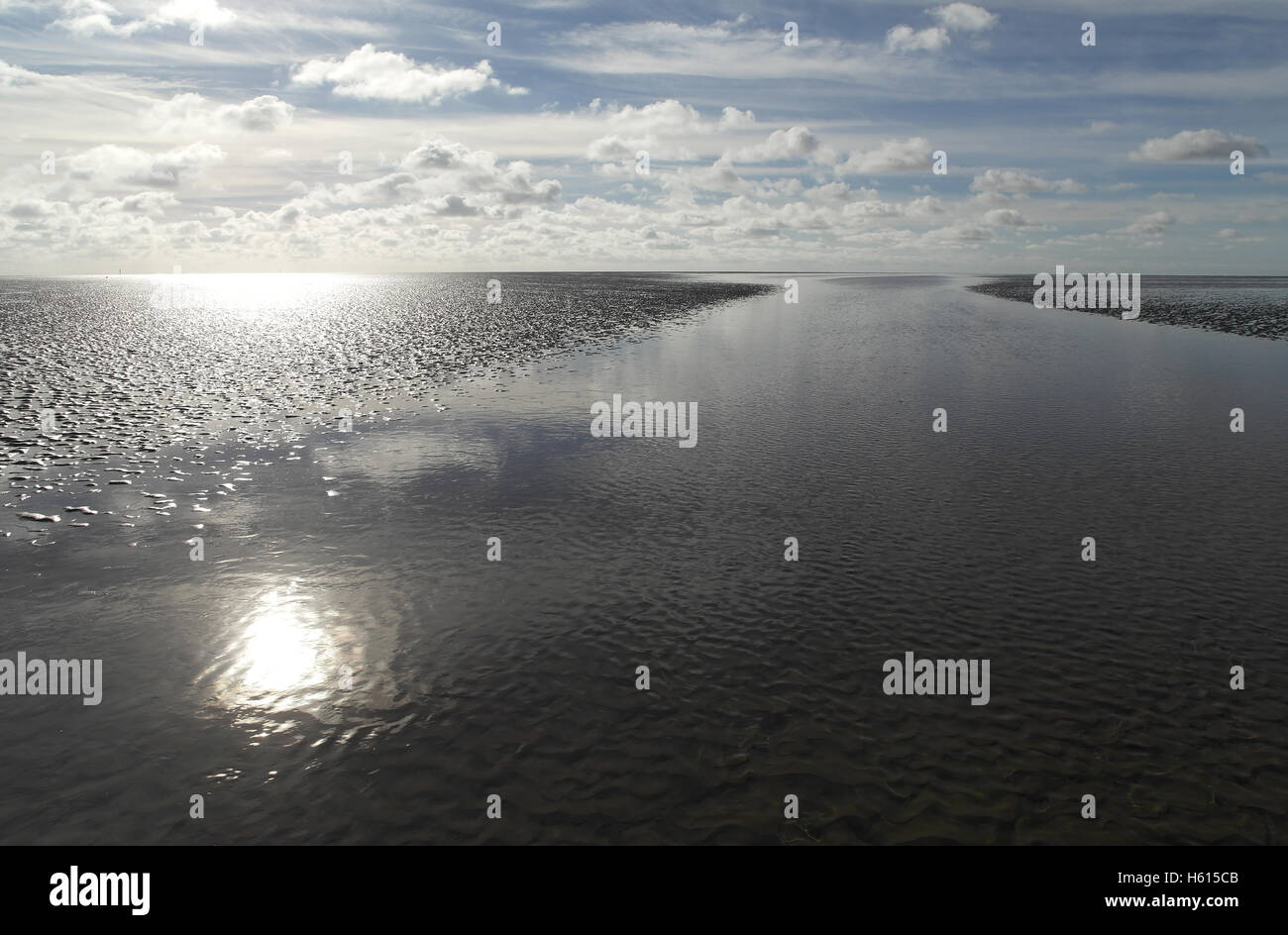 White sun reflection in wide sea water channel crossing sand beach ...