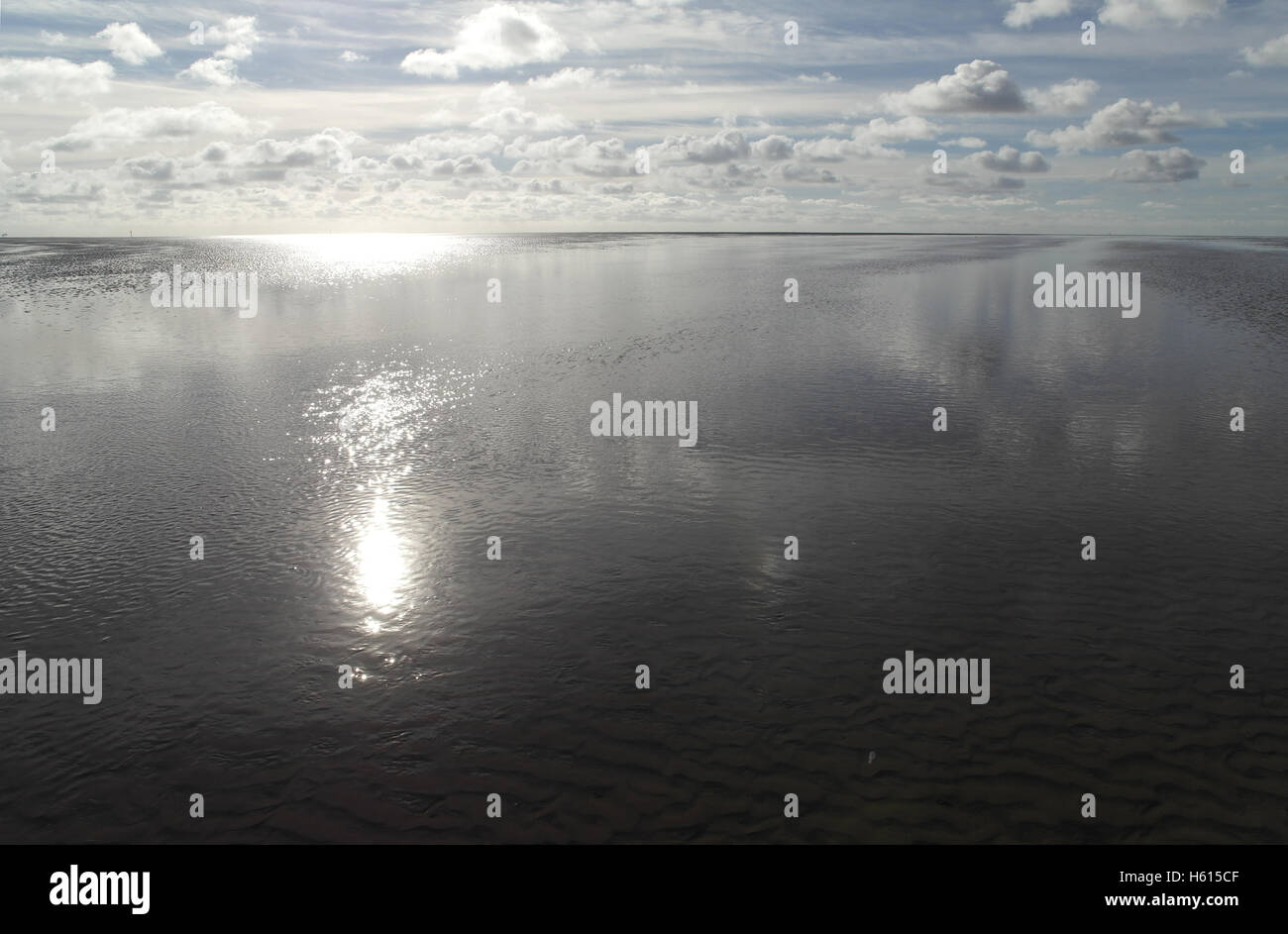 Wide sea water channel with white sun reflection crossing sand beach ...